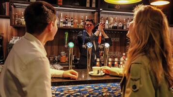 Uma área de bar com um bartender, um balcão e prateleiras cheias de garrafas.