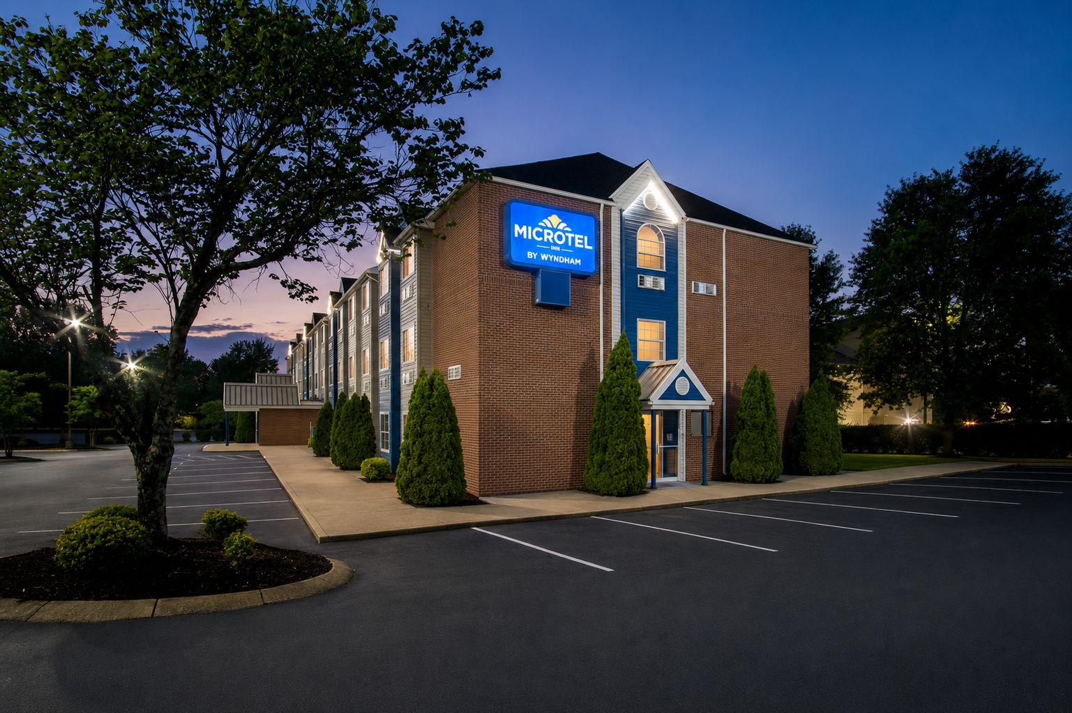 Edifício do Microtel Inn by Wyndham com estacionamento e árvores.