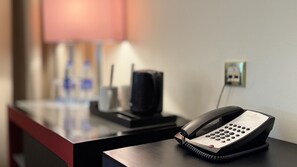 Balcão de recepção de hotel com telefone, abajur e tomada na parede.