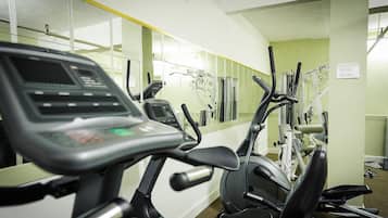 Uma academia com diversos aparelhos de ginástica, incluindo esteiras e elípticos, dispostos em fila.