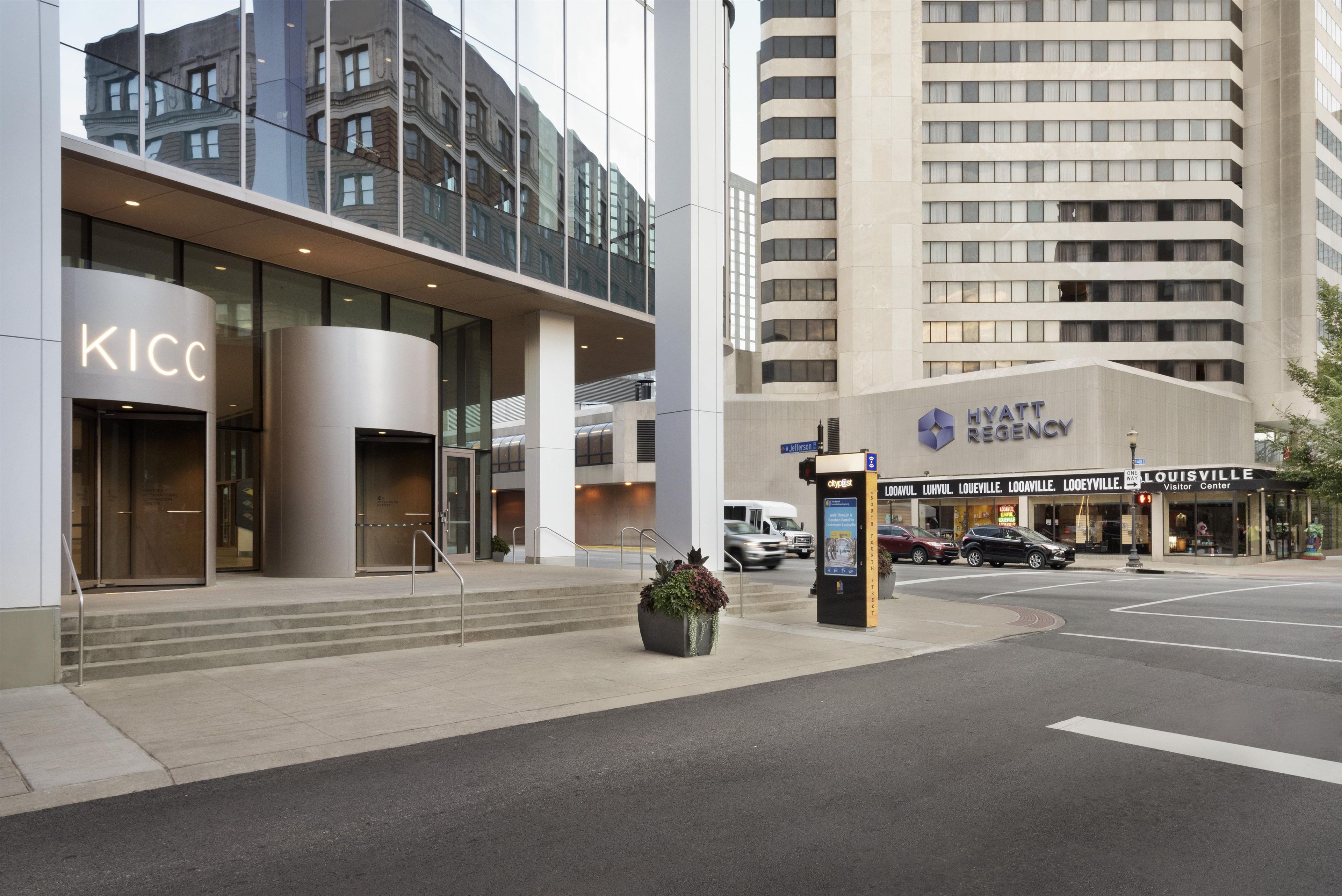 Um hotel moderno com a placa KICC, a placa Hyatt Regency e um centro de visitantes.
