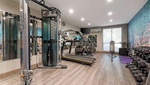 Uma academia moderna com diversos equipamentos de exercício, incluindo esteira, aparelhos de musculação e halteres.