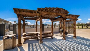Uma pérgola de madeira com bancos e um contentor de lixo.