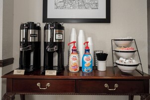 Uma estação de café com duas máquinas de café, copos descartáveis e garrafas de leite para café.