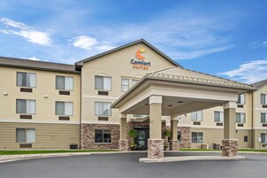Um hotel com fachada bege, entrada coberta e uma placa com a inscrição 'Comfort Suites'.