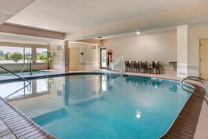 Piscina com deck azulejado, área de estar coberta com cadeiras e porta que dá para outro quarto.