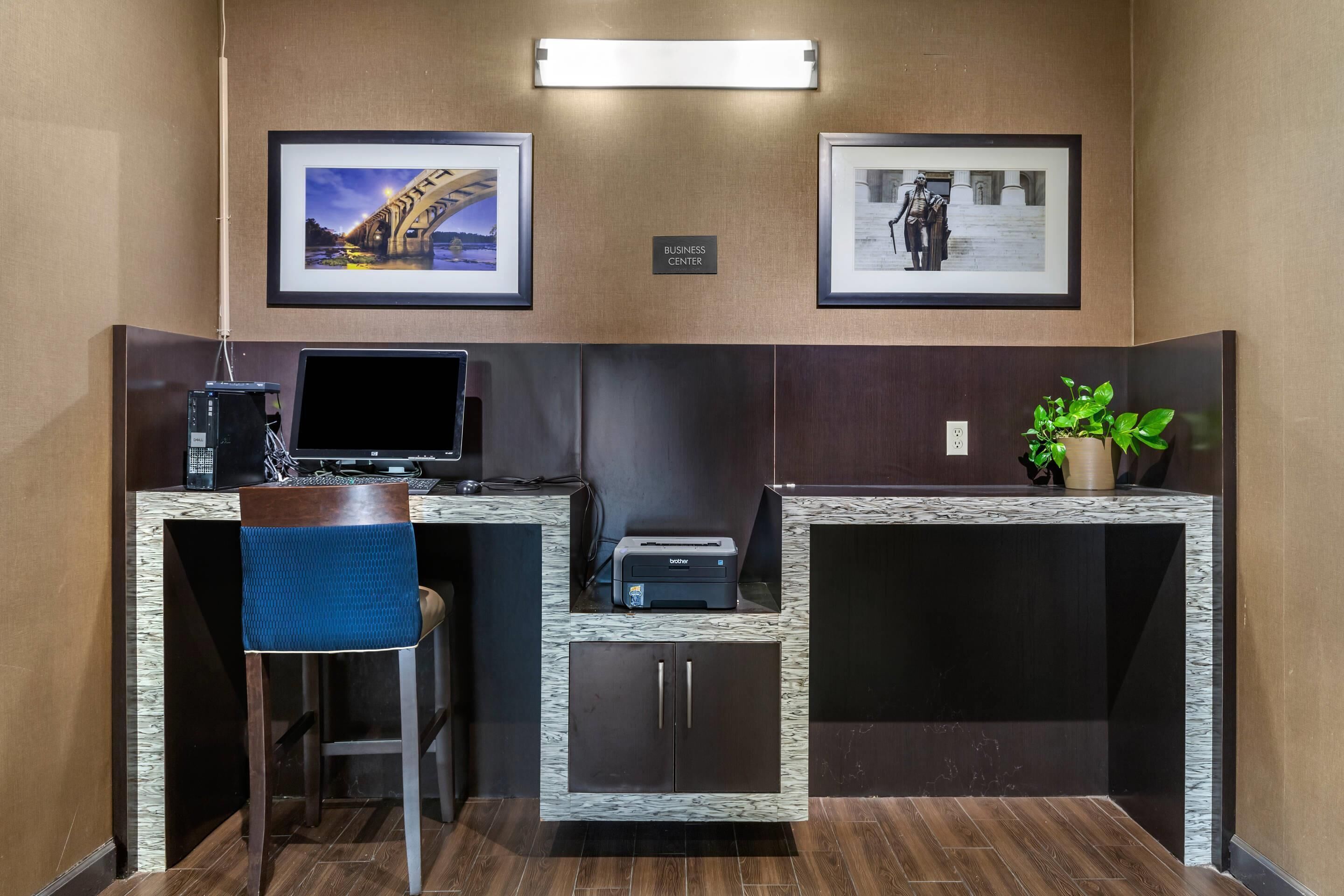 Espaço de negócios com mesa, impressora e quadros na parede.