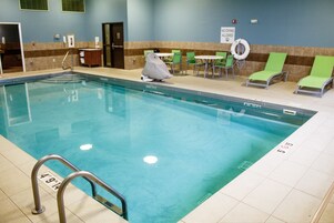 Piscina interna com cadeira de salva-vidas, cadeiras de descanso e placa indicando que mergulhos não são permitidos.