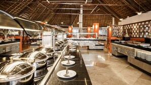 Disposição de buffet com várias estações de serviço, teto alto com vigas aparentes e design de parede estampado.