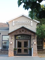 Staybridge Suites com entrada destacada, pilares de pedra e uma placa visível sobre as portas.