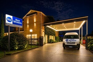 Um hotel Best Western com entrada coberta e veículo de serviço de transporte.