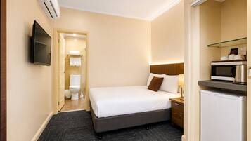 Quarto de hotel com cama, mesa de cabeceira, televisão, micro-ondas e mini-geladeira.