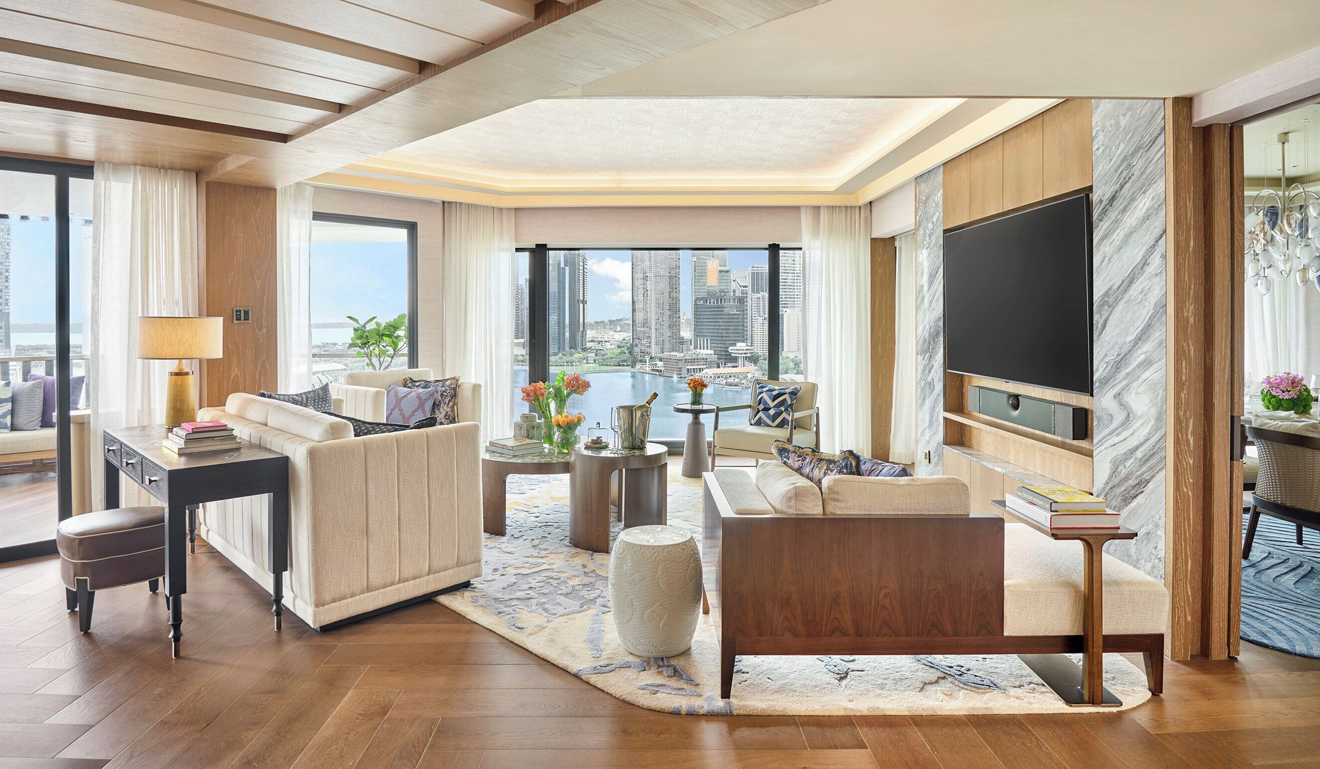Uma sala de estar ampla com uma televisão grande, assentos confortáveis, vista para a cidade e um design moderno.