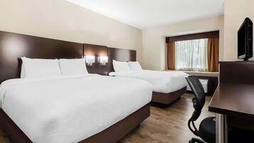 Quarto de hotel com duas camas, uma escrivaninha, uma cadeira e uma televisão.