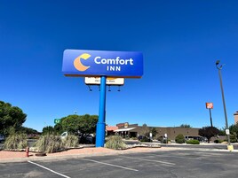 Placa do Comfort Inn com vista clara do estacionamento e edifícios ao redor.