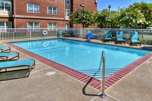 Piscina com cadeiras azuis e cerca branca.