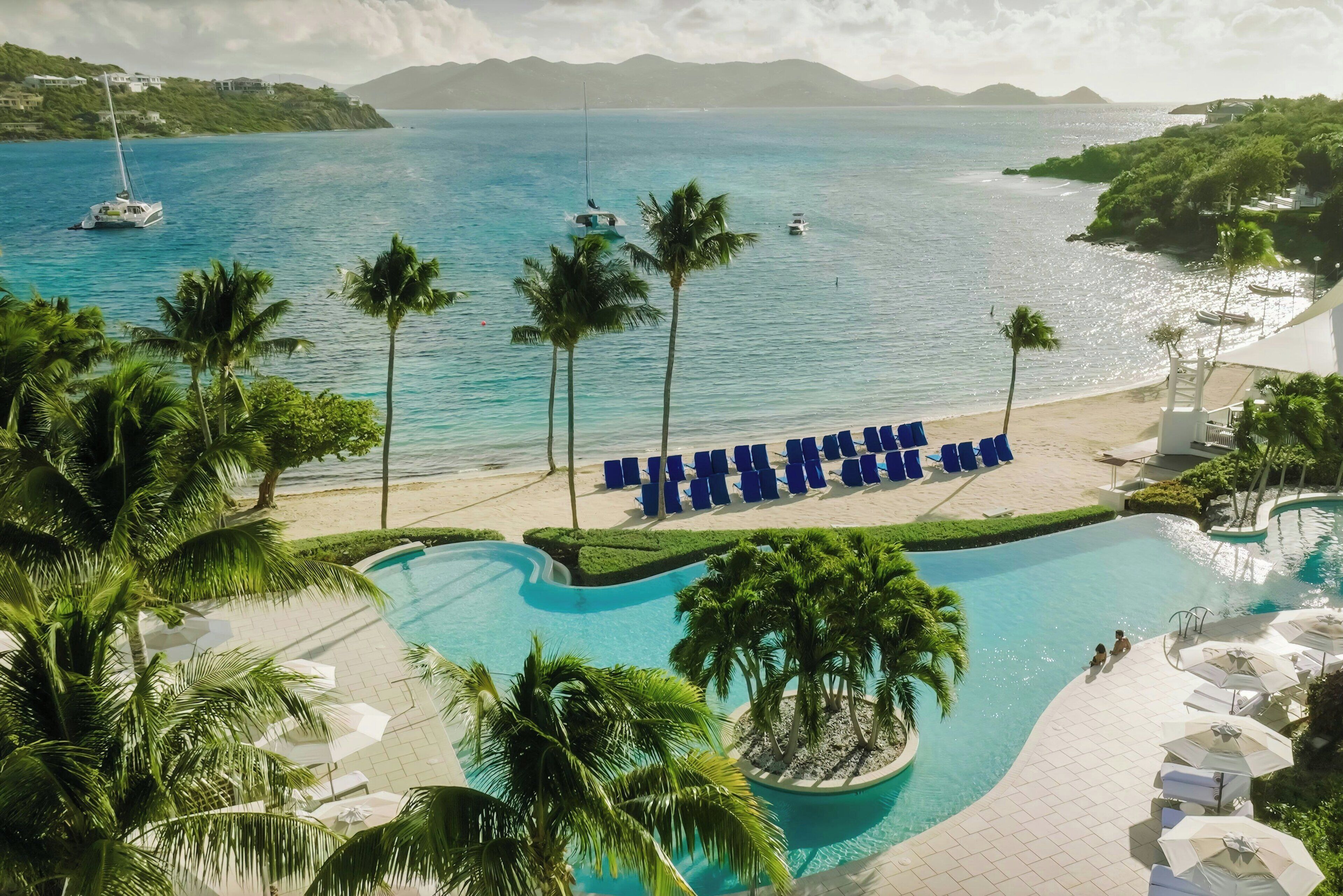 Um resort com piscina, cadeiras de praia e palmeiras.