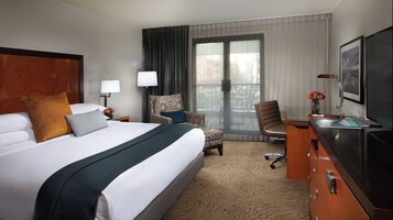 Quarto de hotel com uma cama grande, uma mesa, uma cadeira e uma televisão.