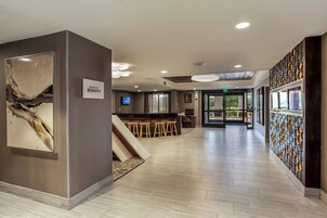 Um lobby de hotel moderno com área de bar, uma grande pintura abstrata e um letreiro do hotel Marriott Bonvoy.