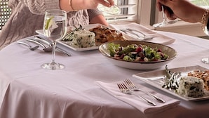 Mesa de jantar com toalha branca, pratos de comida e copos de vinho.