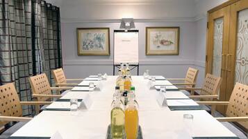 Sala de conferências com uma mesa comprida, cadeiras, placas de identificação e um banner.