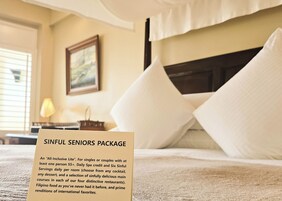 Quarto de hotel com cama bem arrumada, mesa de cabeceira com abajur e quadro na parede.