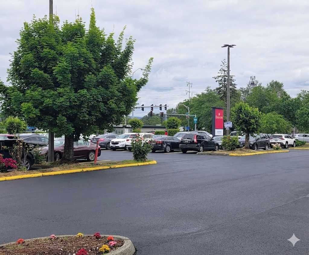 Um parque de estacionamento com carros, uma placa vermelha e árvores.