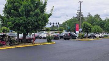 Um parque de estacionamento com carros, uma placa vermelha e árvores.