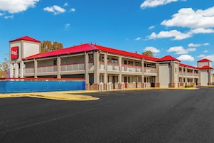 Um hotel com telhado vermelho, várias varandas e uma cerca azul em frente.