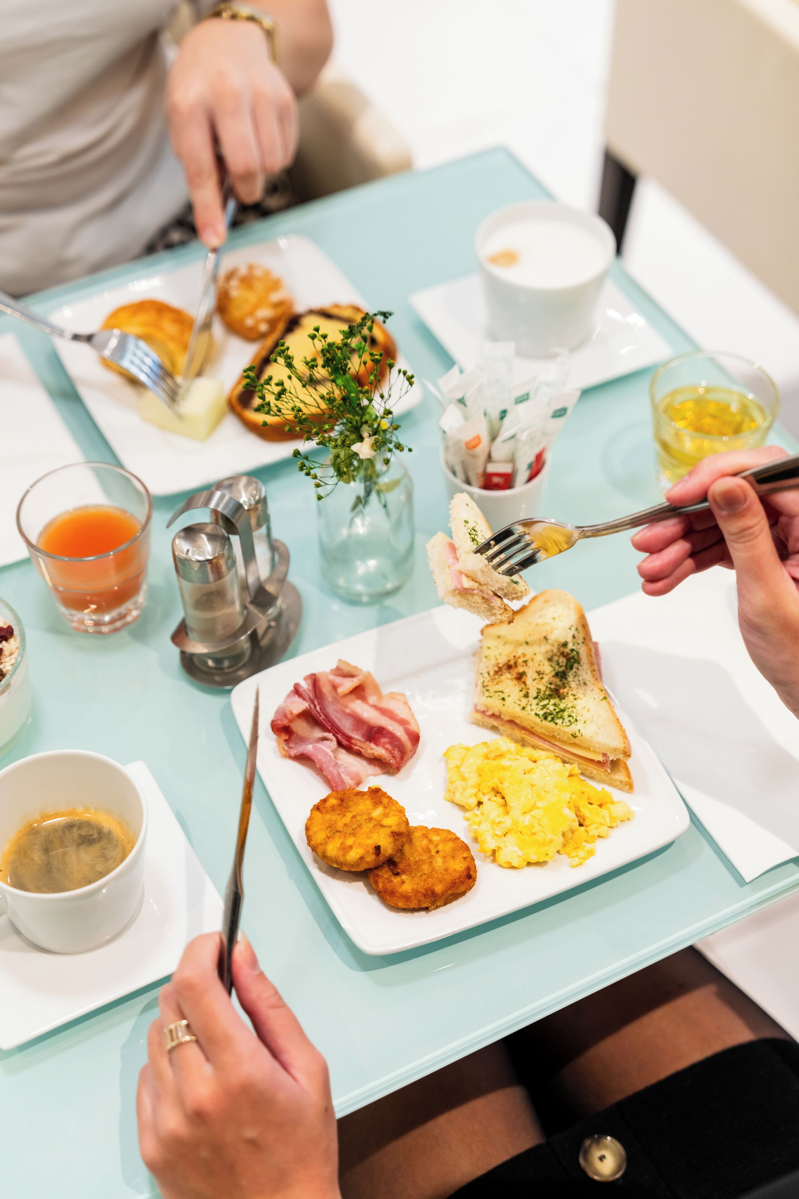Uma mesa de café da manhã com diversos pratos, incluindo torradas, ovos mexidos e bacon.