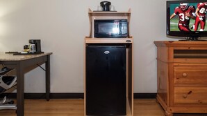 Uma cozinha compacta com micro-ondas, geladeira e cafeteira em uma pequena mesa.