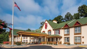 Um hotel com telhado vermelho, uma placa indicando altura livre de 9 pés e uma bandeira americana.