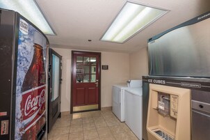 Quarto de hotel com frigorífico, máquina de vendas, porta e chão em azulejo.