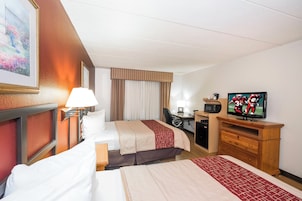 Quarto de hotel com duas camas, uma escrivaninha, televisão e um quadro na parede.