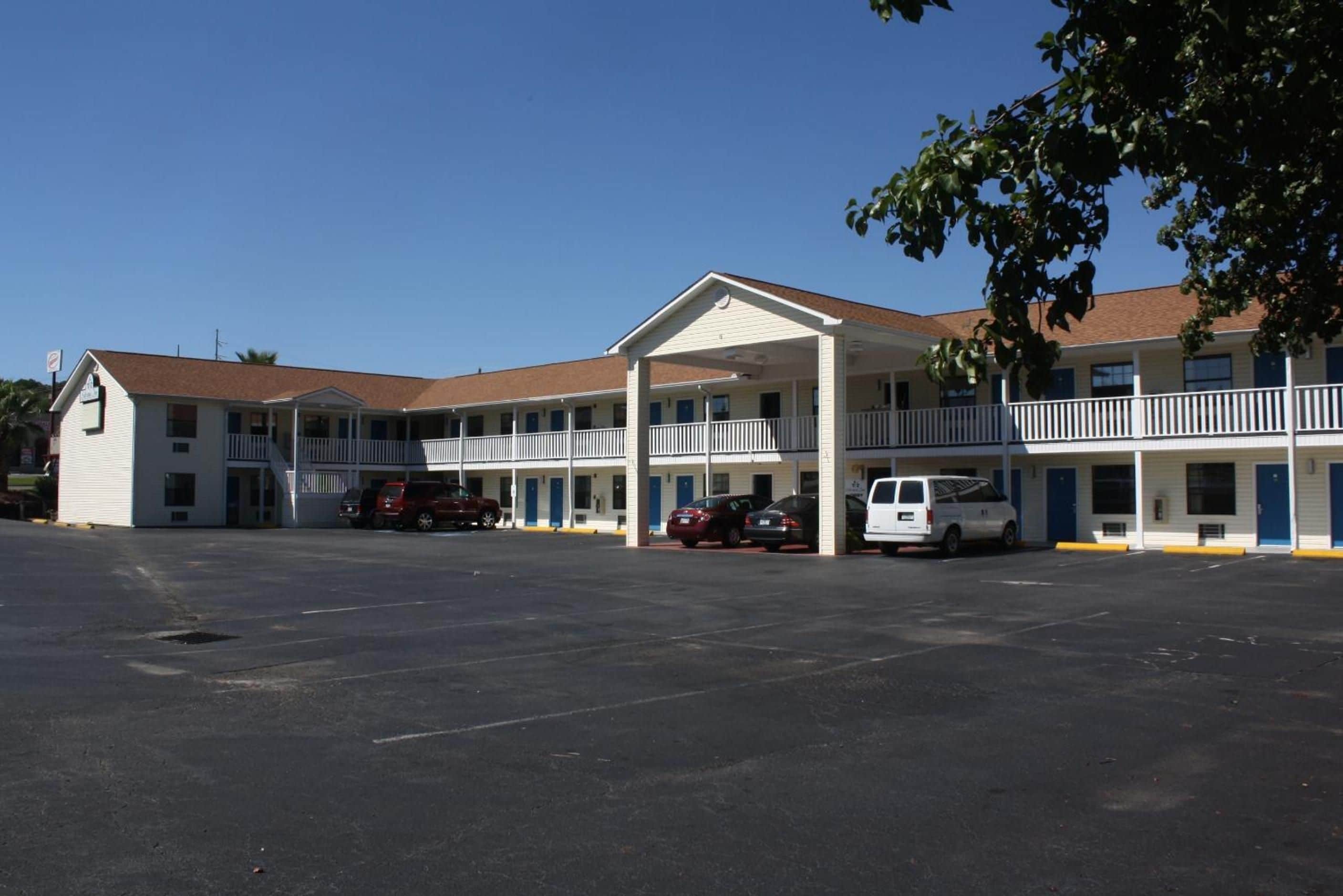 Um motel com estacionamento coberto e vários quartos.