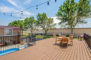 Um deck de madeira com piscina, área de estar externa e luzes de Natal.
