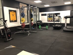 Uma academia com equipamentos de musculação, esteiras e um espelho fixado na parede.