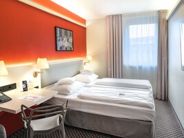 Quarto de hotel com cama, duas mesas de cabeceira, escrivaninha e uma cadeira.