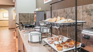Disposição de buffet com diversos produtos de panificação e um canto de café.