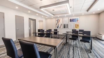 Uma sala de conferências com uma mesa comprida, várias cadeiras e piso coberto de carpete.