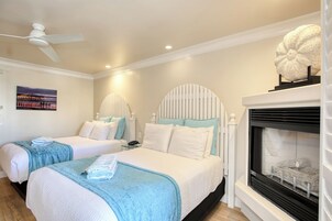 Quarto de hotel com duas camas, lareira e ventoinha no teto.
