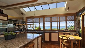 Cozinha com uma ilha grande, armários de madeira e vista para o mar.
