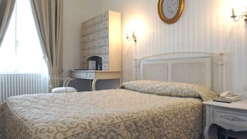 Quarto de hotel com cama, escrivaninha, cadeira, cômoda e mesa de cabeceira.