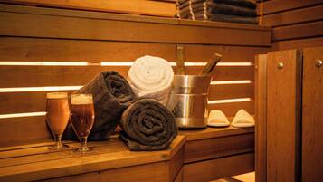 Uma sauna com bancos de madeira, toalhas e um balde de água.