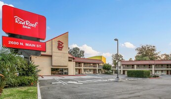 Um Red Roof Inn com uma grande placa vermelha, estacionamento e um edifício com telhado vermelho.