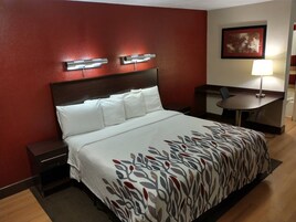 Quarto de hotel com uma cama grande, uma mesa de cabeceira, uma escrivaninha e uma cadeira.