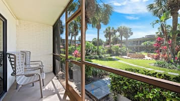 Uma varanda com vista para um jardim bem cuidado, incluindo palmeiras e diversas plantas.