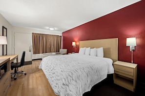 Quarto de hotel com cama, mesas de cabeceira, escrivaninha e uma cadeira.