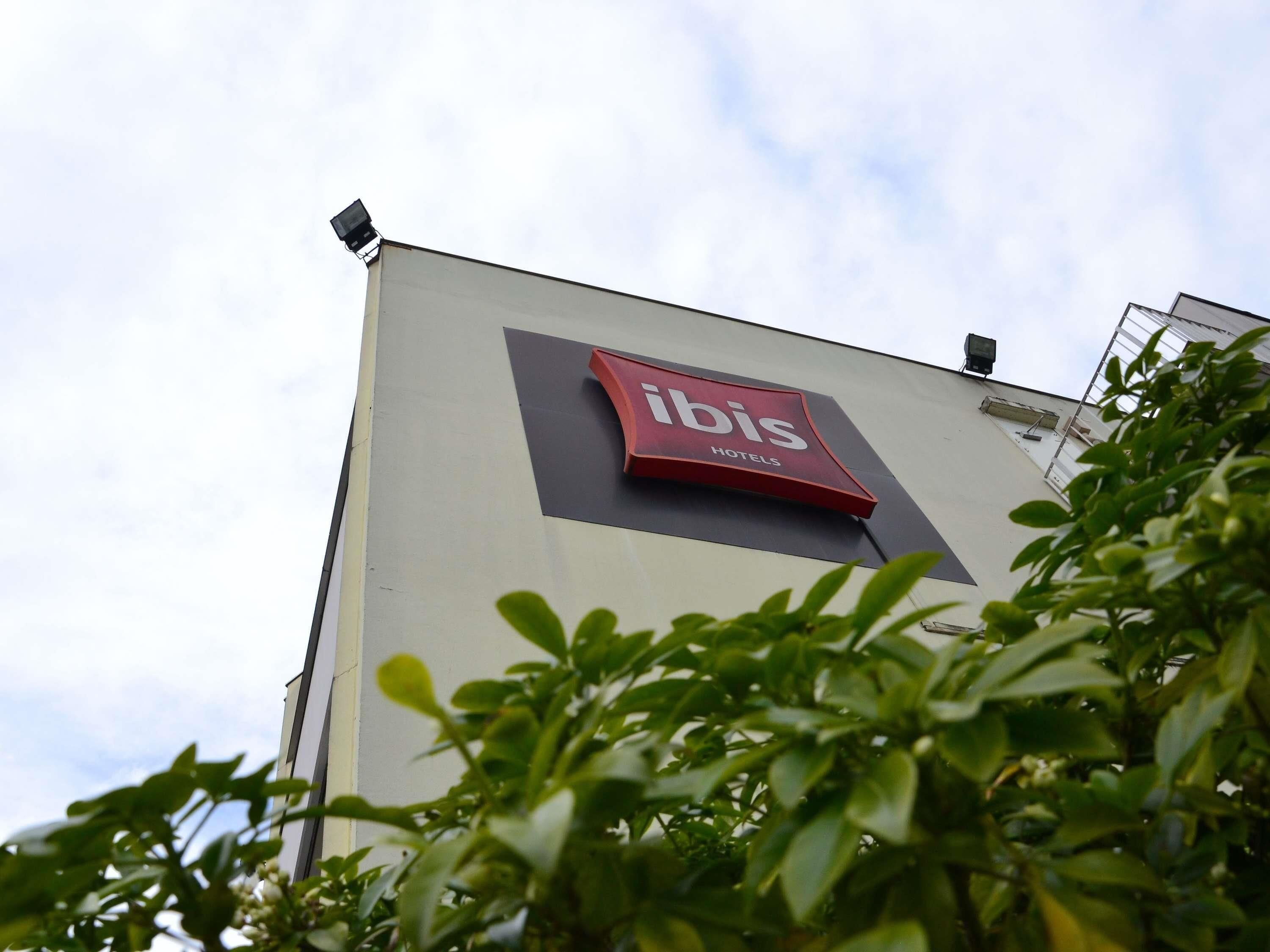 Um edifício com a fachada exibindo a placa 'ibis Hotels'.