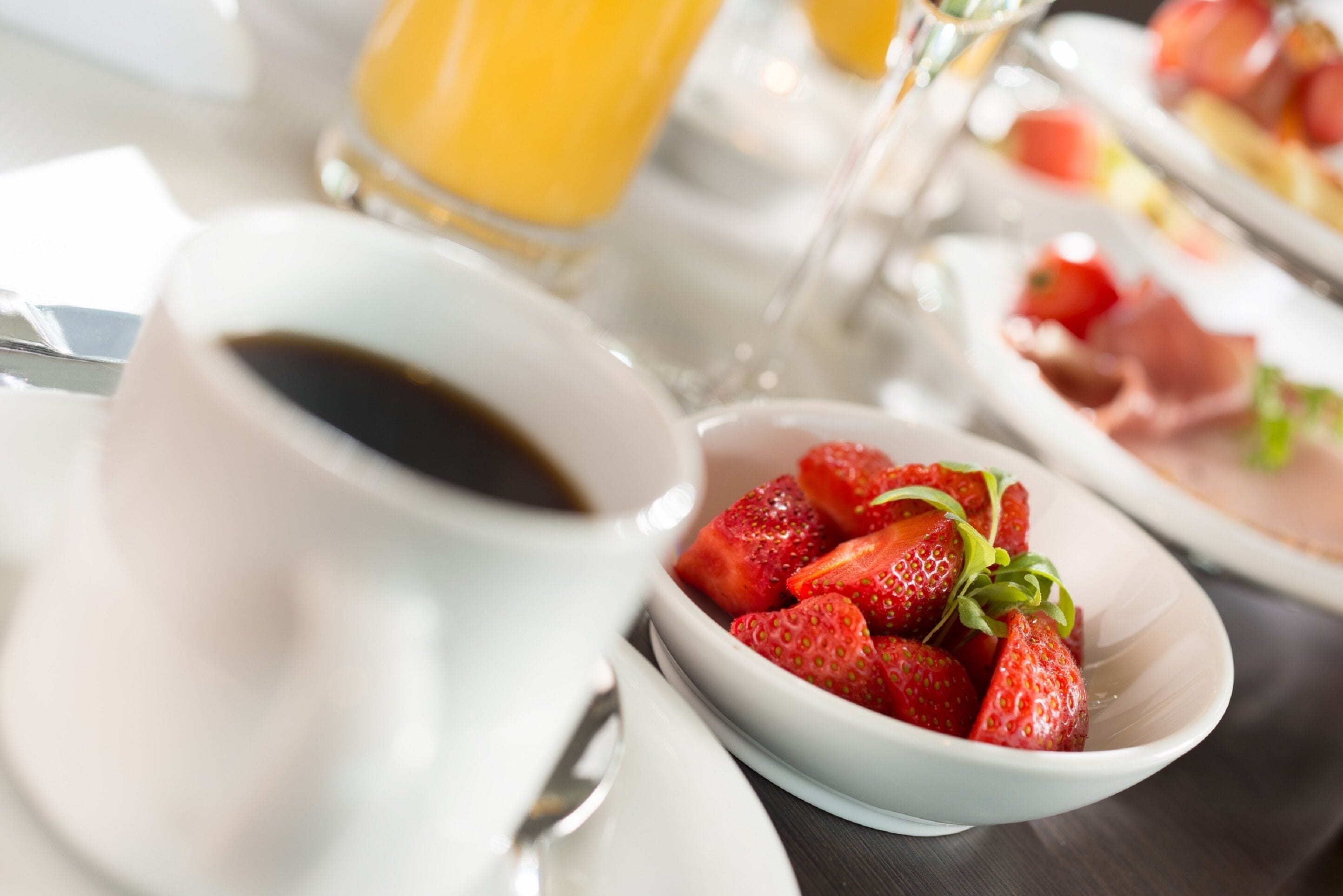 Uma mesa com café, morangos e suco de laranja para o café da manhã.